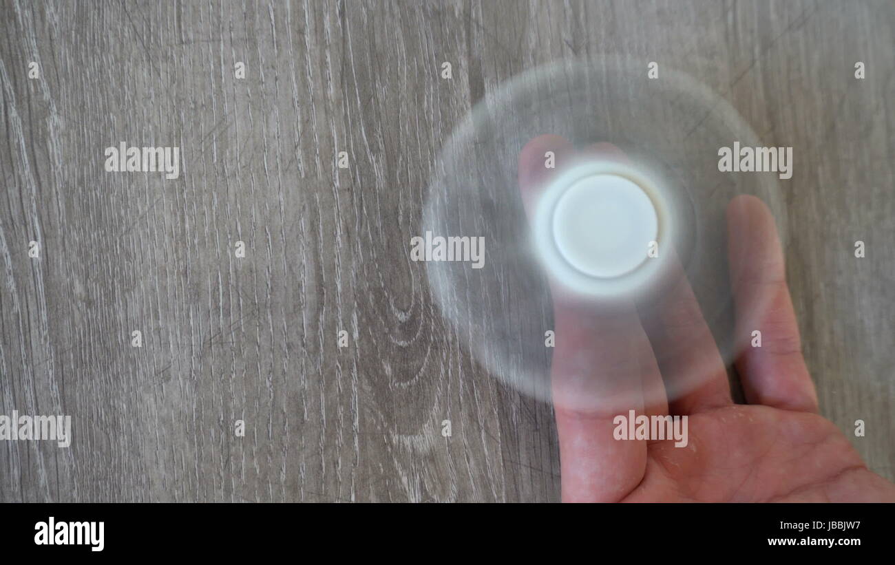 white hand spinner, or fidgeting spinner, rotating on man's hand Stock ...