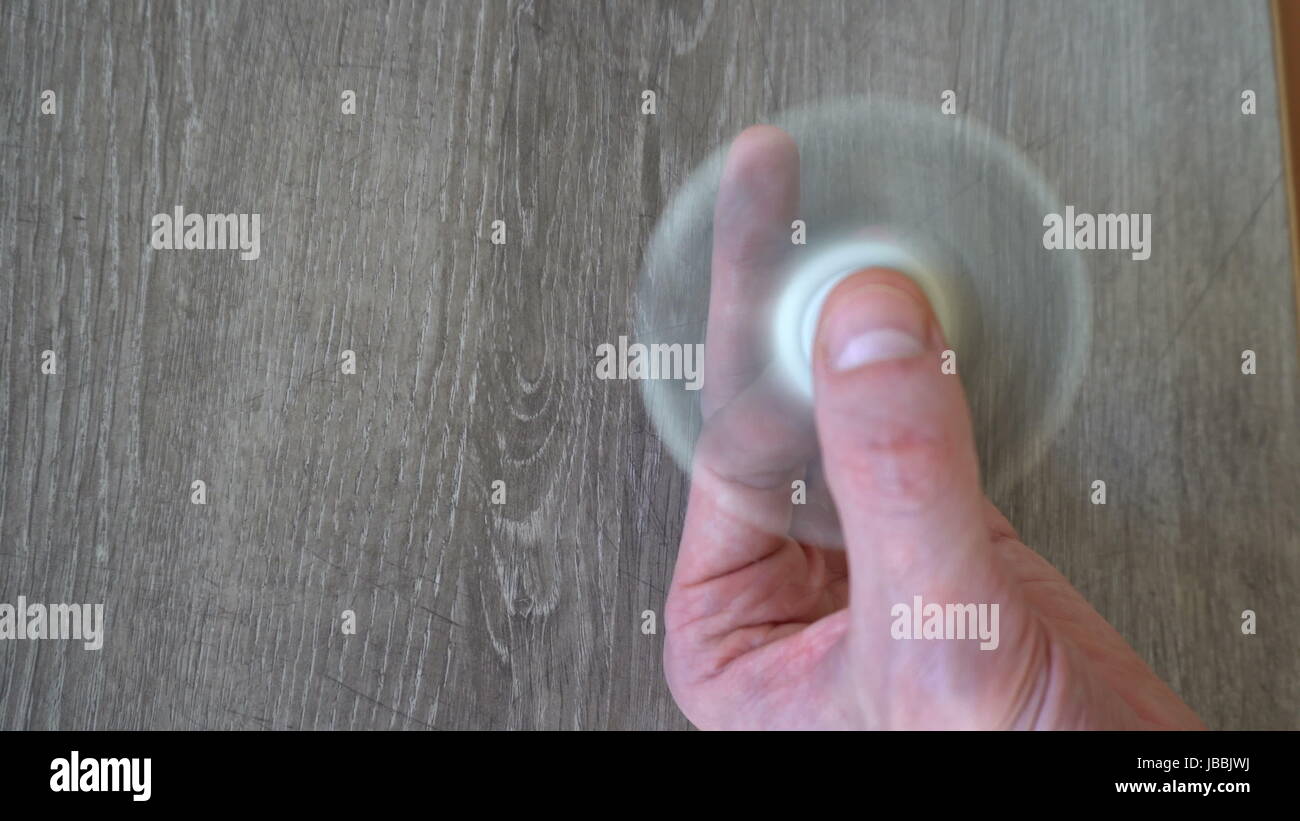 white hand spinner, or fidgeting spinner, rotating on man's hand Stock ...