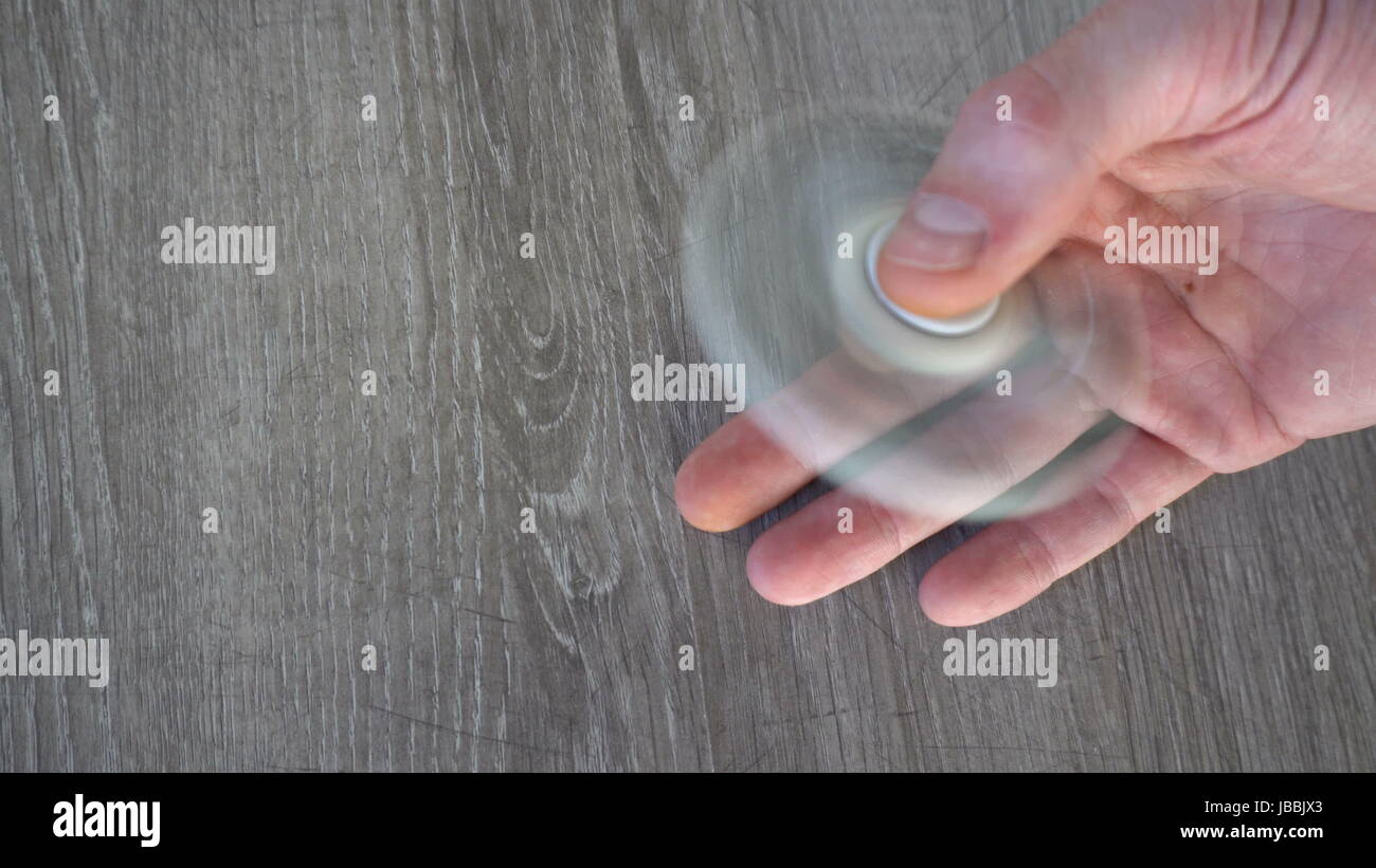 white hand spinner, or fidgeting spinner, rotating on man's hand Stock ...