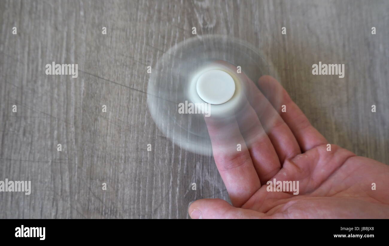white hand spinner, or fidgeting spinner, rotating on man's hand Stock ...