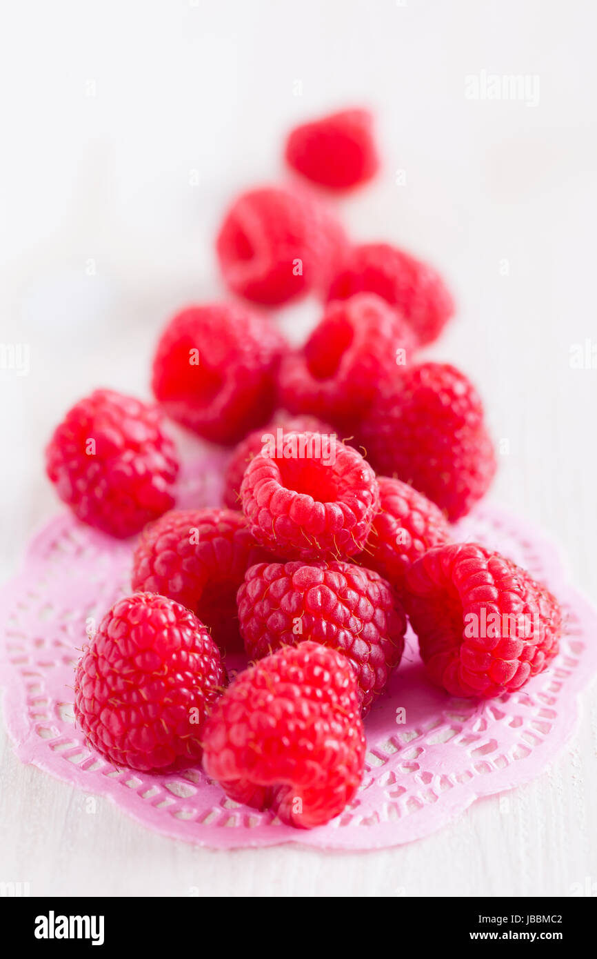Closeup of bunch of fresh red raspberries resting on decorative pink ...