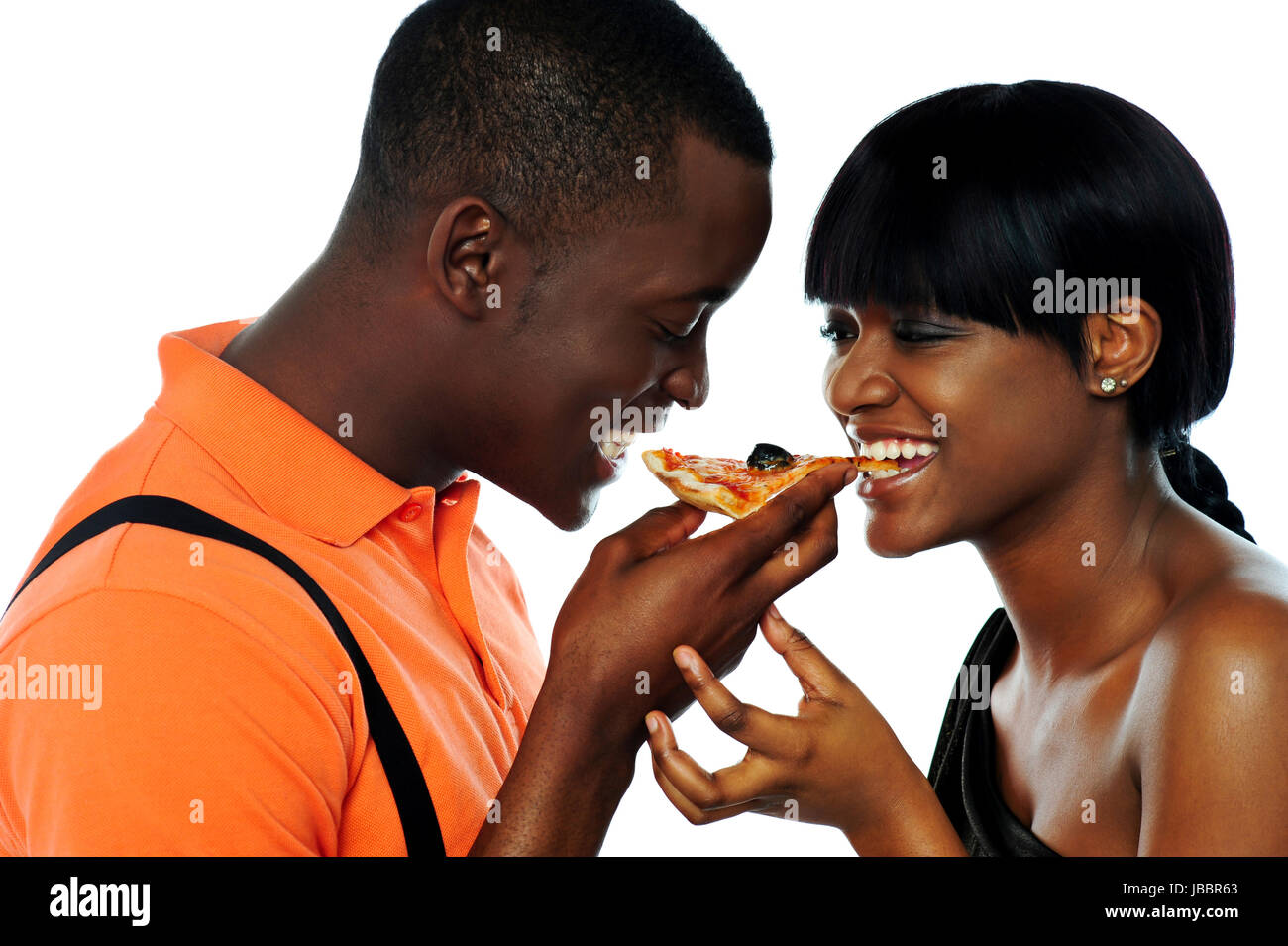 Young couple sharing a slice of pizza isolated over white background ...