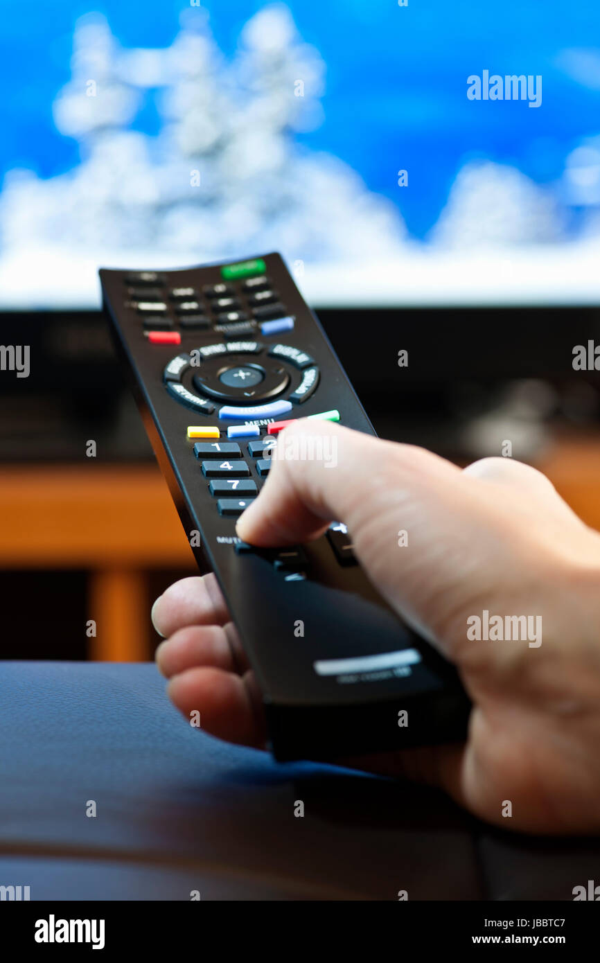 Hand holding television remote control pressing buttons Stock Photo - Alamy