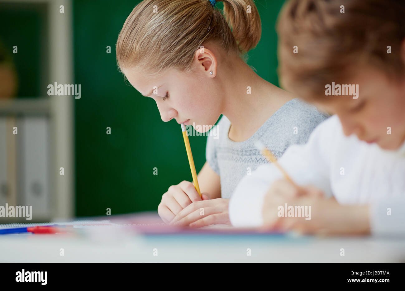 Image of cute girl with pencil thinking of what to draw Stock Photo - Alamy