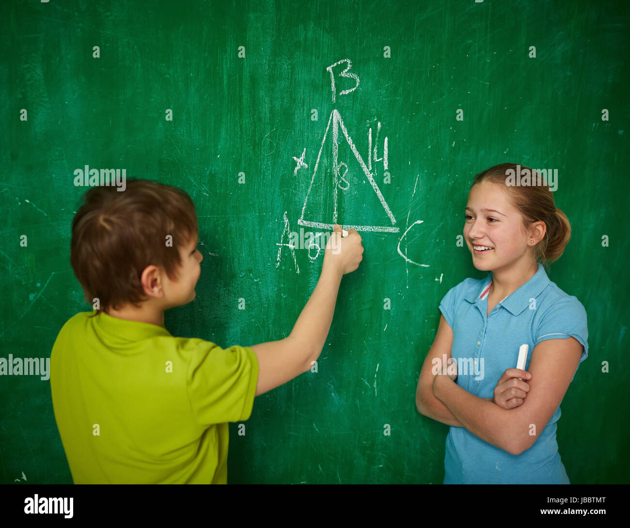 Portrait of two classmates by the blackboard at the lesson of geometry ...