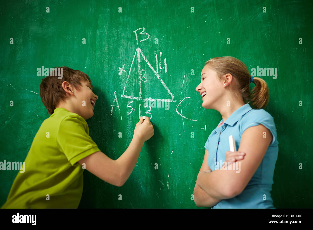 Portrait of two joyful classmates by the blackboard at the lesson of ...