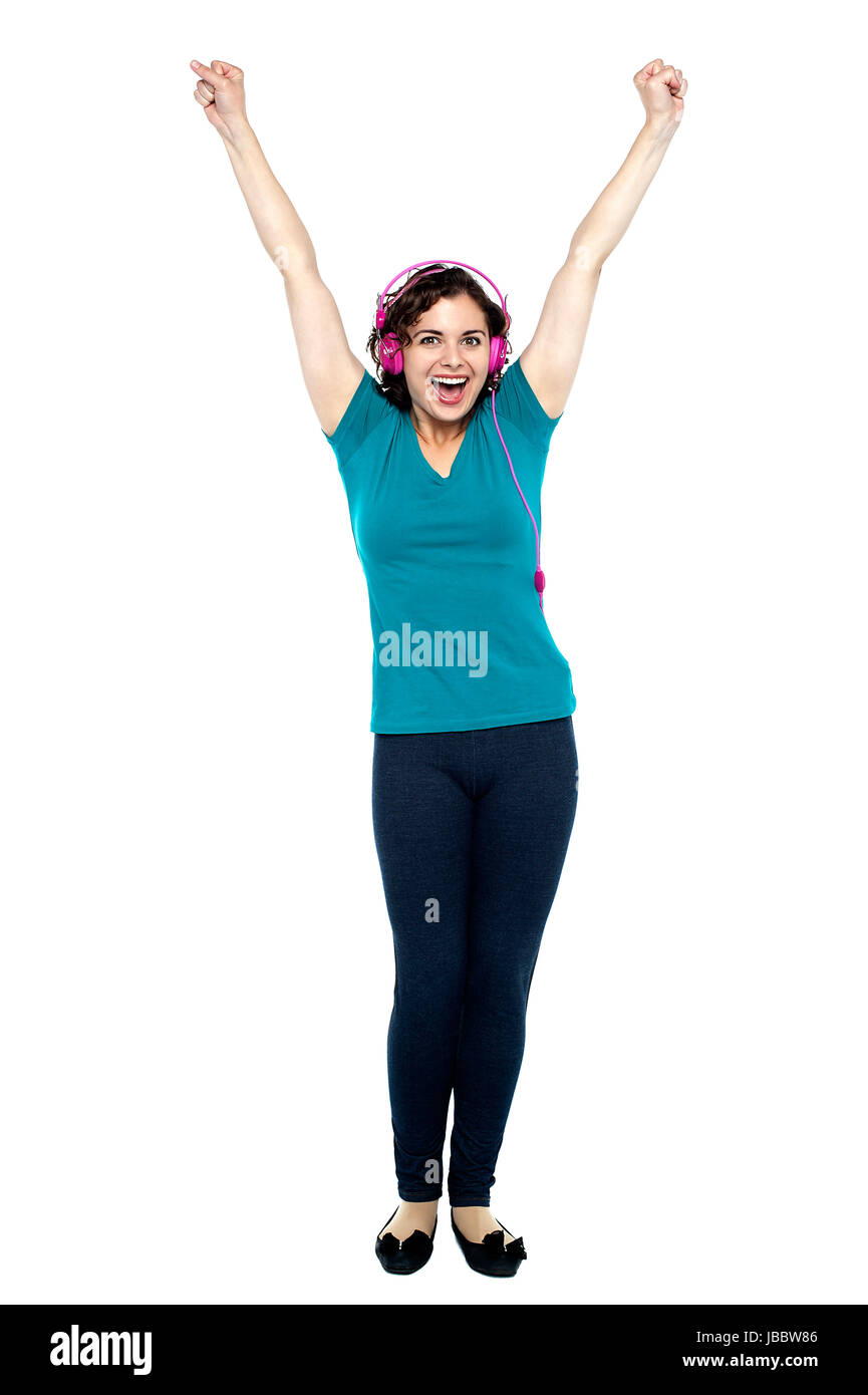 Full length shot of an euphoric music enthusiast throwing up her arms ...