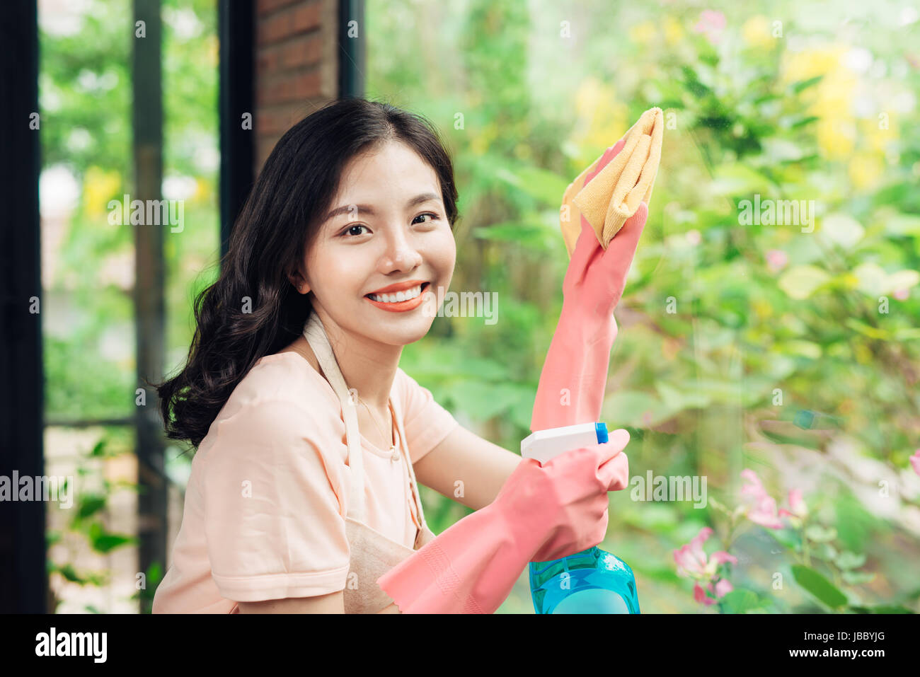 Cleaning concept. Cheerful asian woman cleaning window Stock Photo - Alamy