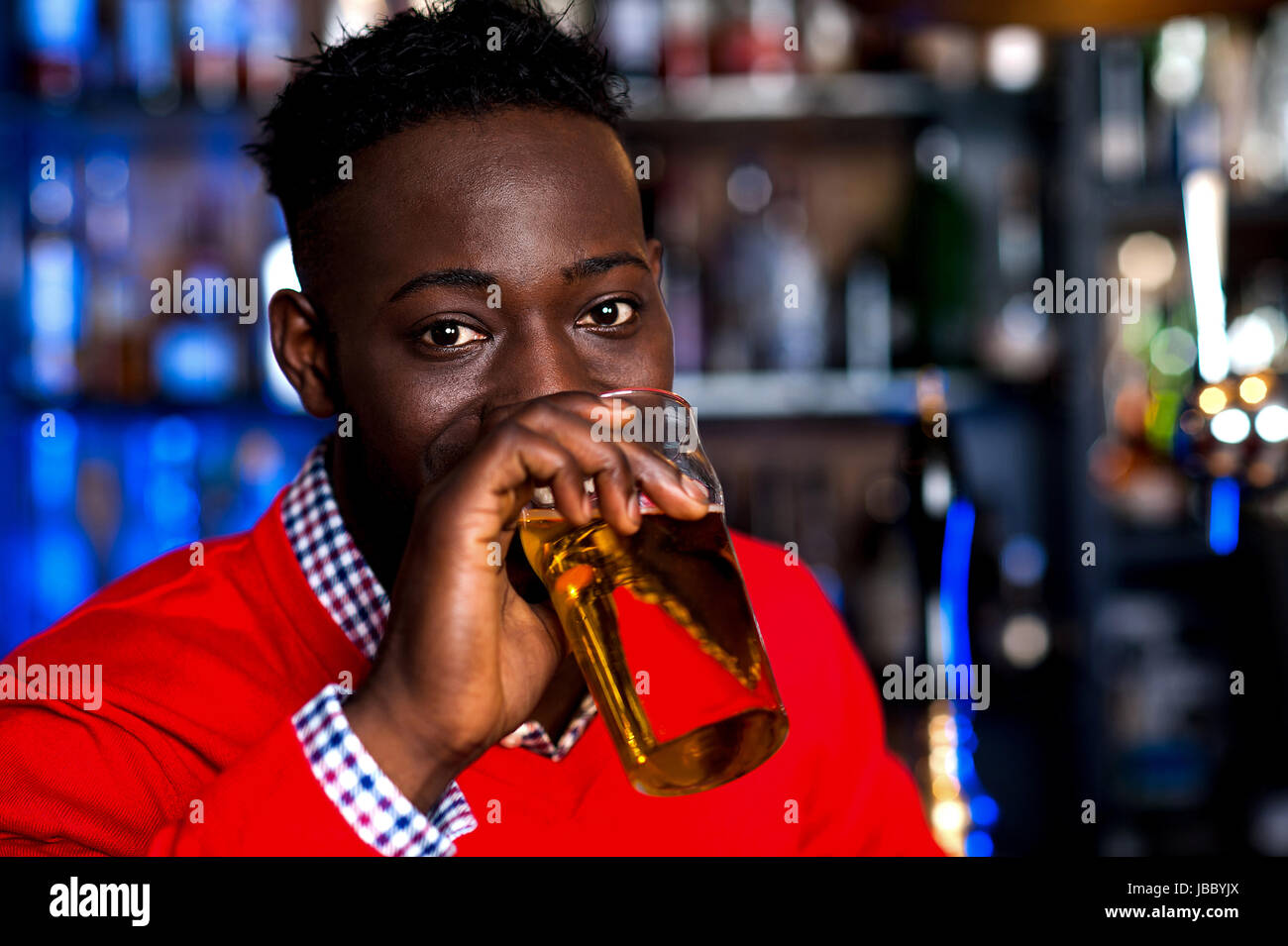 Young african guy drinking beer in nightclub Stock Photo - Alamy