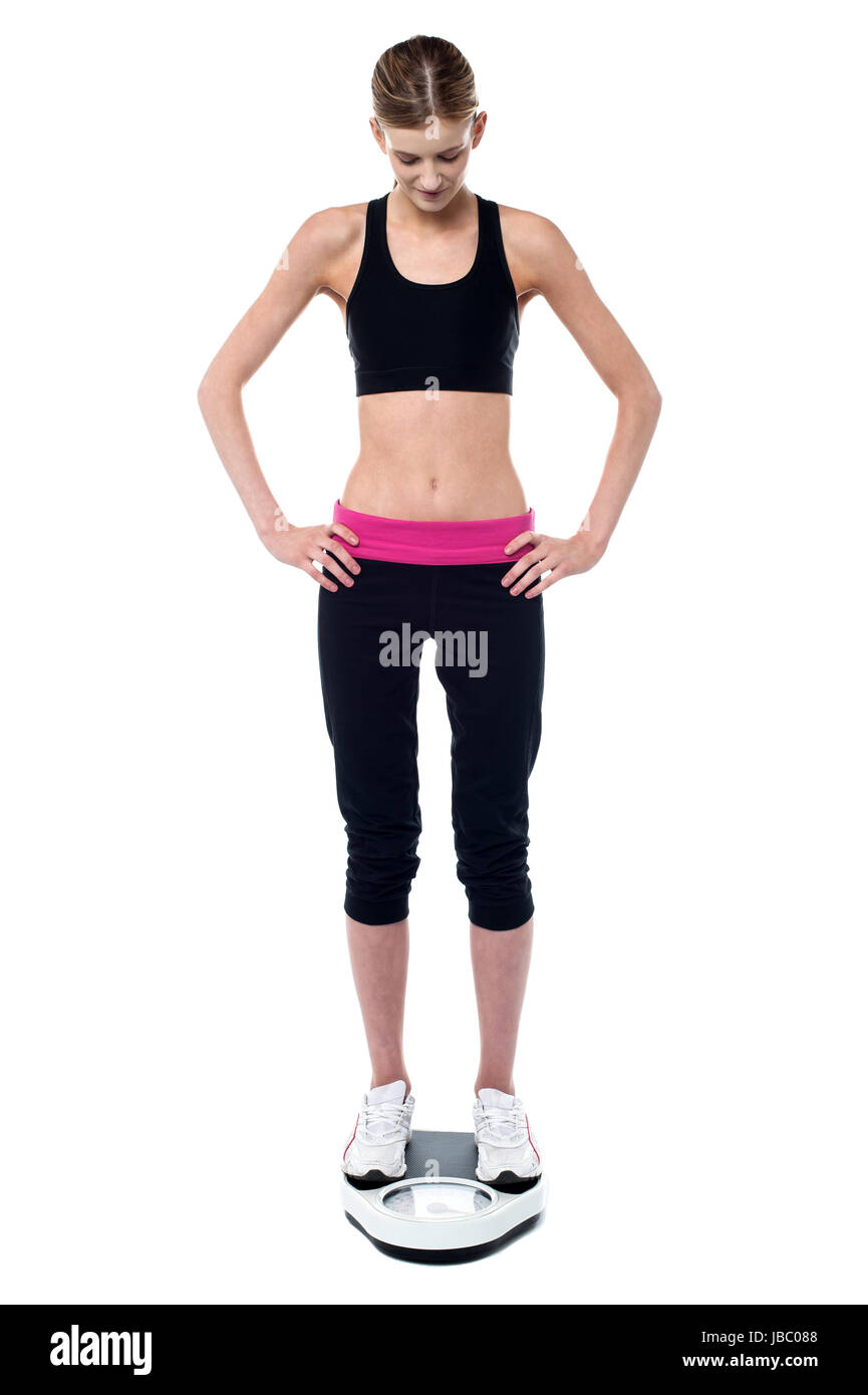 Young girl measuring her weight, standing on weighing scale Stock Photo ...