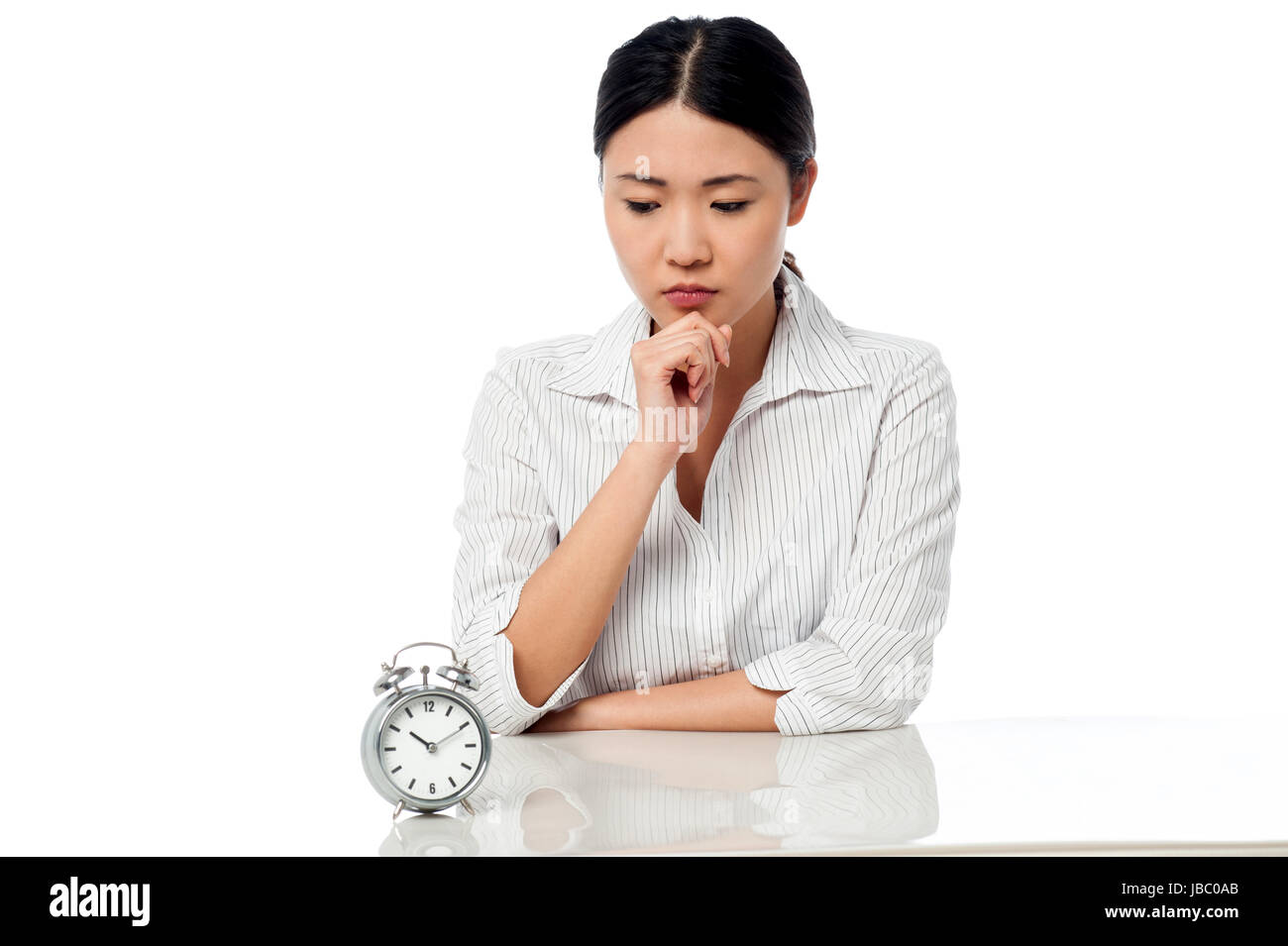 Thoughtful young business person staring at alarm clock Stock Photo - Alamy