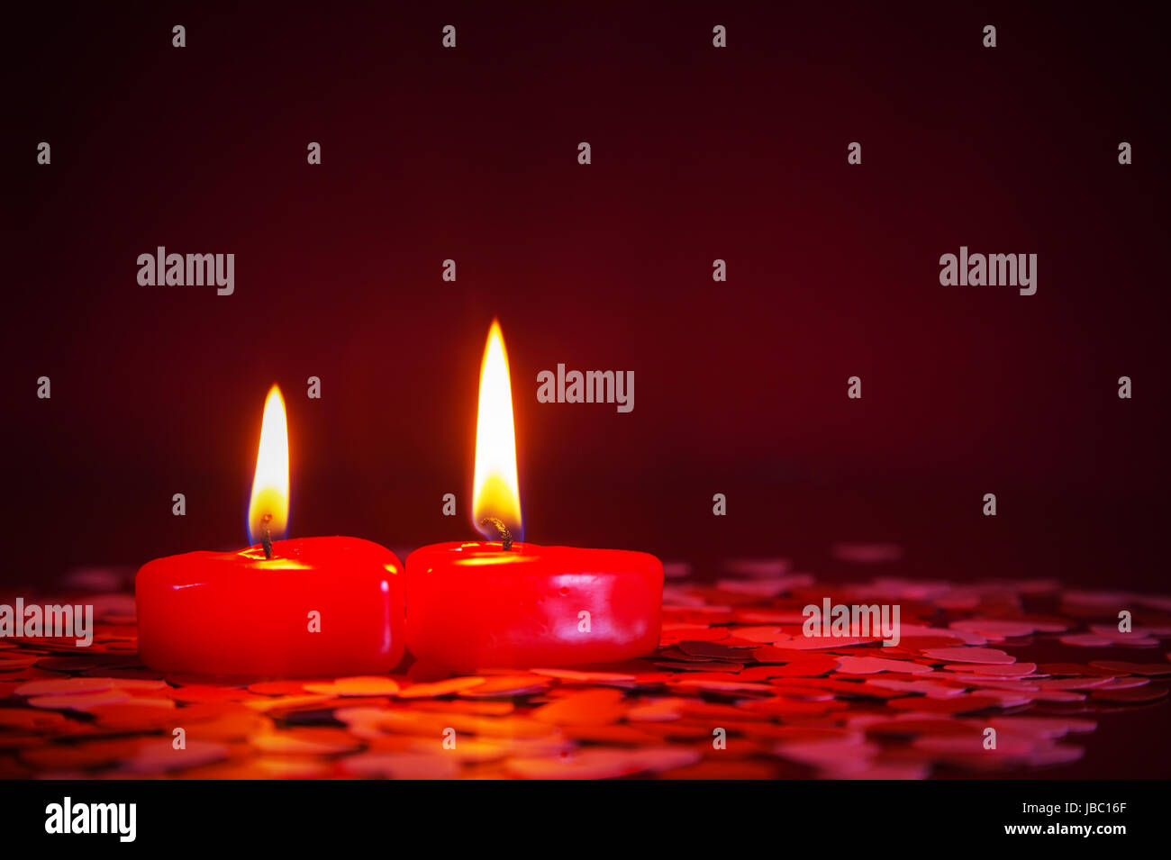 Two red burning candles against dark background Stock Photo - Alamy