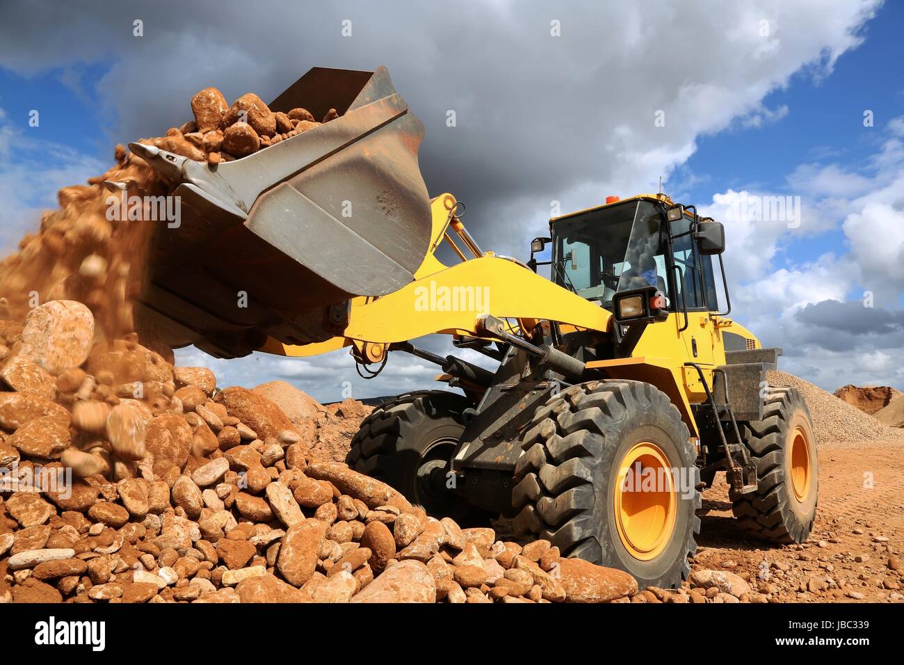 Front end loader dumping stone and sand in a mining quarry Stock Photo ...
