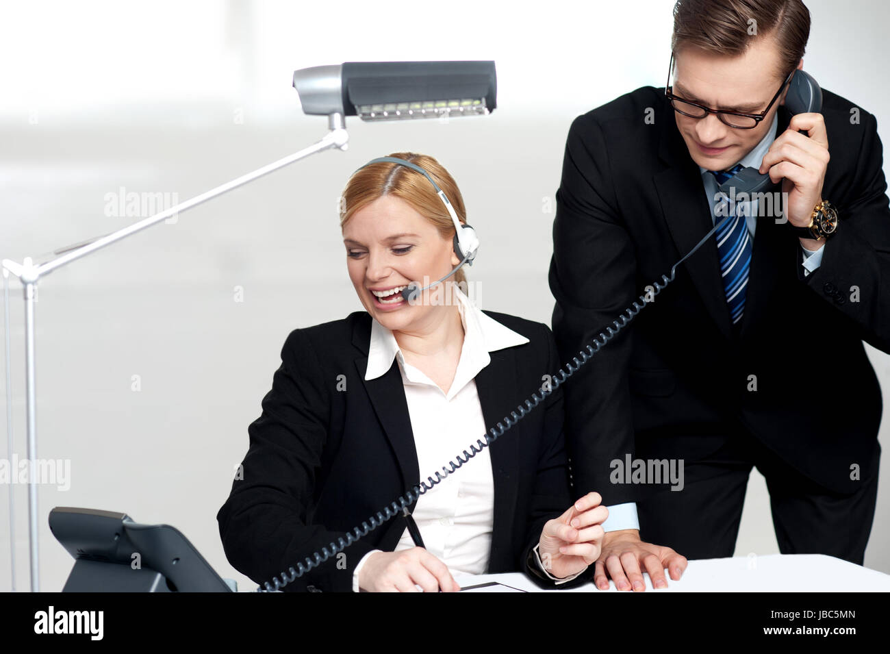 Male executive attending clients call while female secretary enjoys the ...