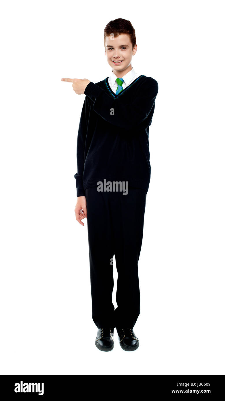 Full length portrait of attractive school boy pointing towards copy ...