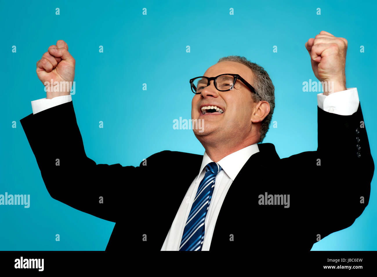 Portrait of a successful businessman with his hands raised against ...