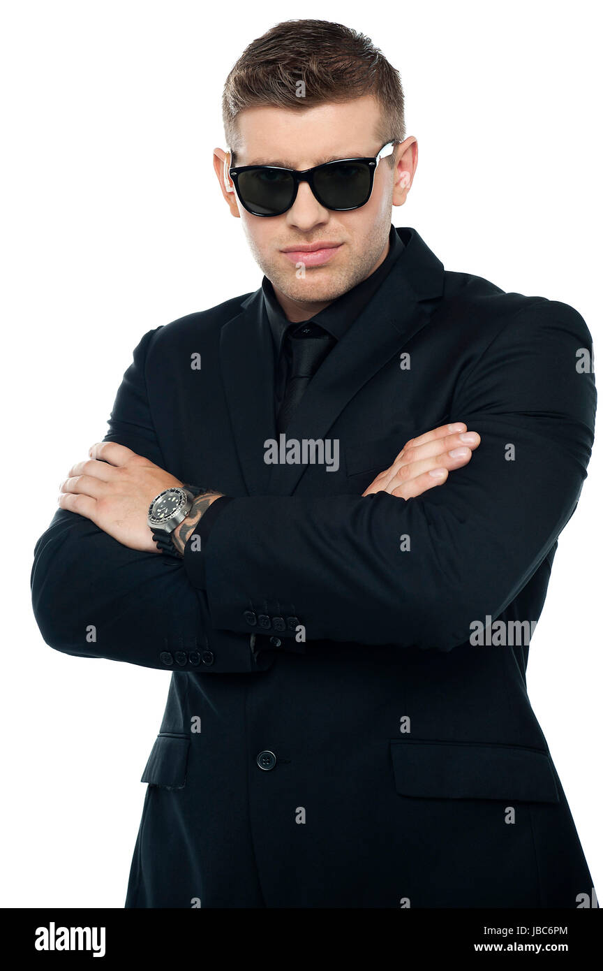 Young stylish bouncer in a black suit, arms folded. Half length ...