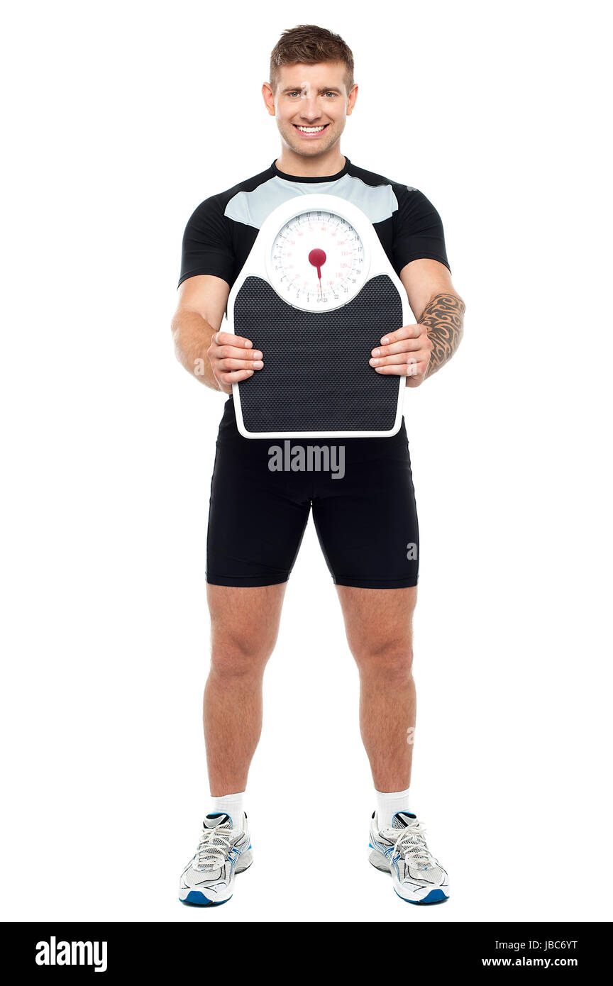 Attractive athlete showing weighing scale against white background ...