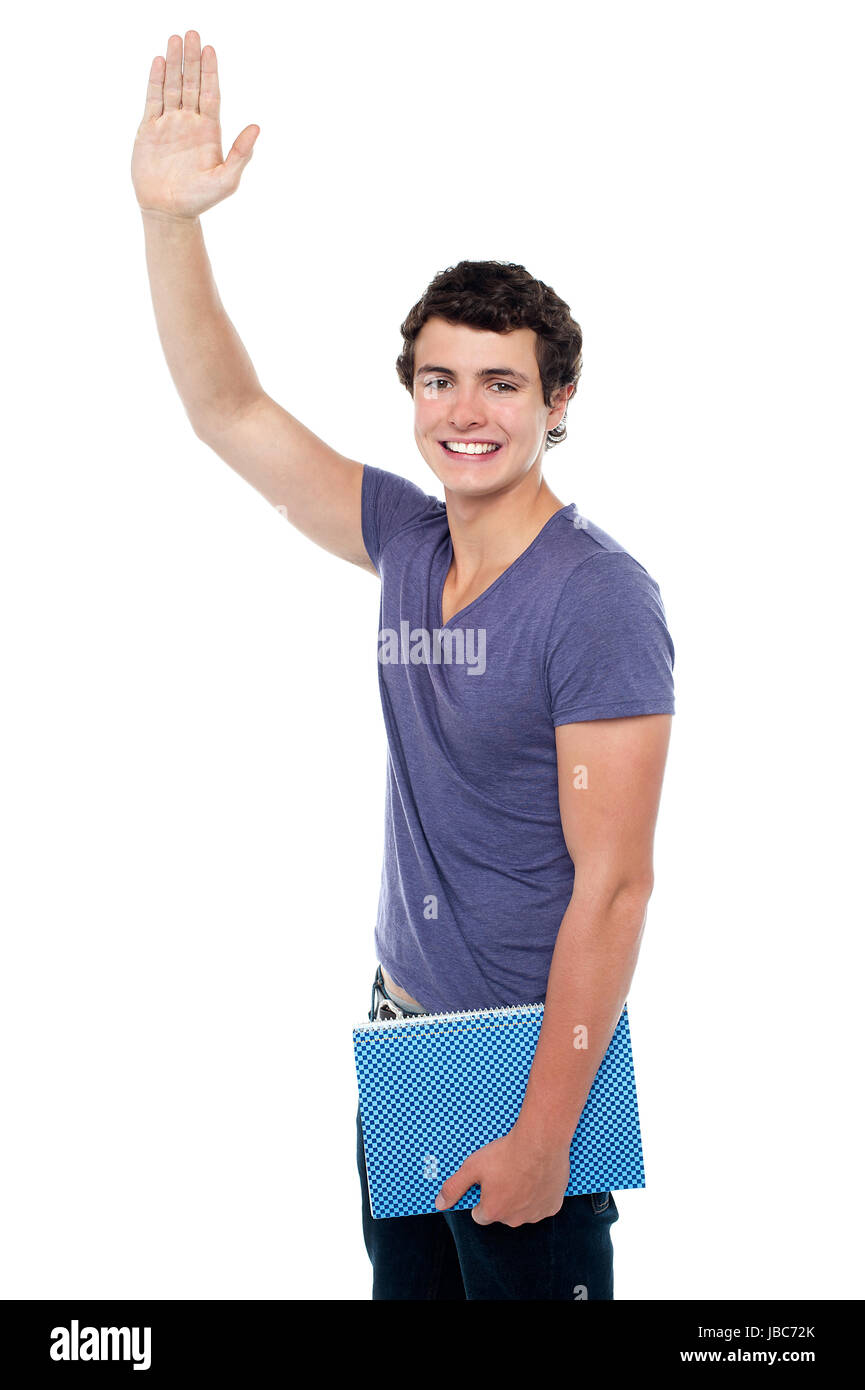 Handsome young guy with a notebook in hand putting his right hand up ...