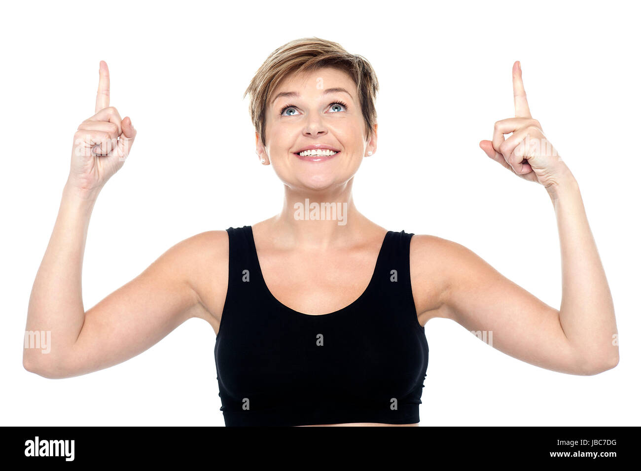 Woman looking and pointing upwards with both hands. Studio shot Stock ...