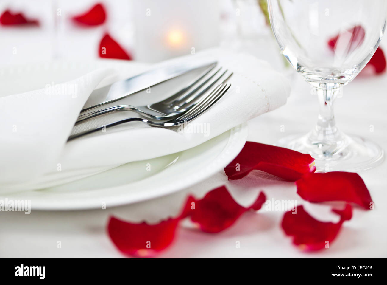 Romantic table setting with rose petals plates and cutlery Stock Photo ...