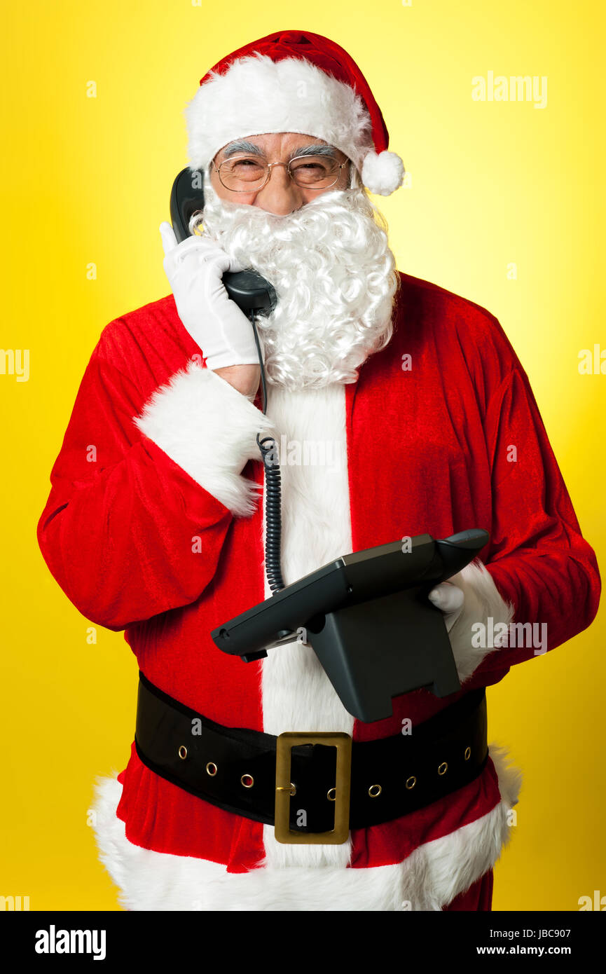 Smiling aged Santa attending phone call isolated against yellow ...