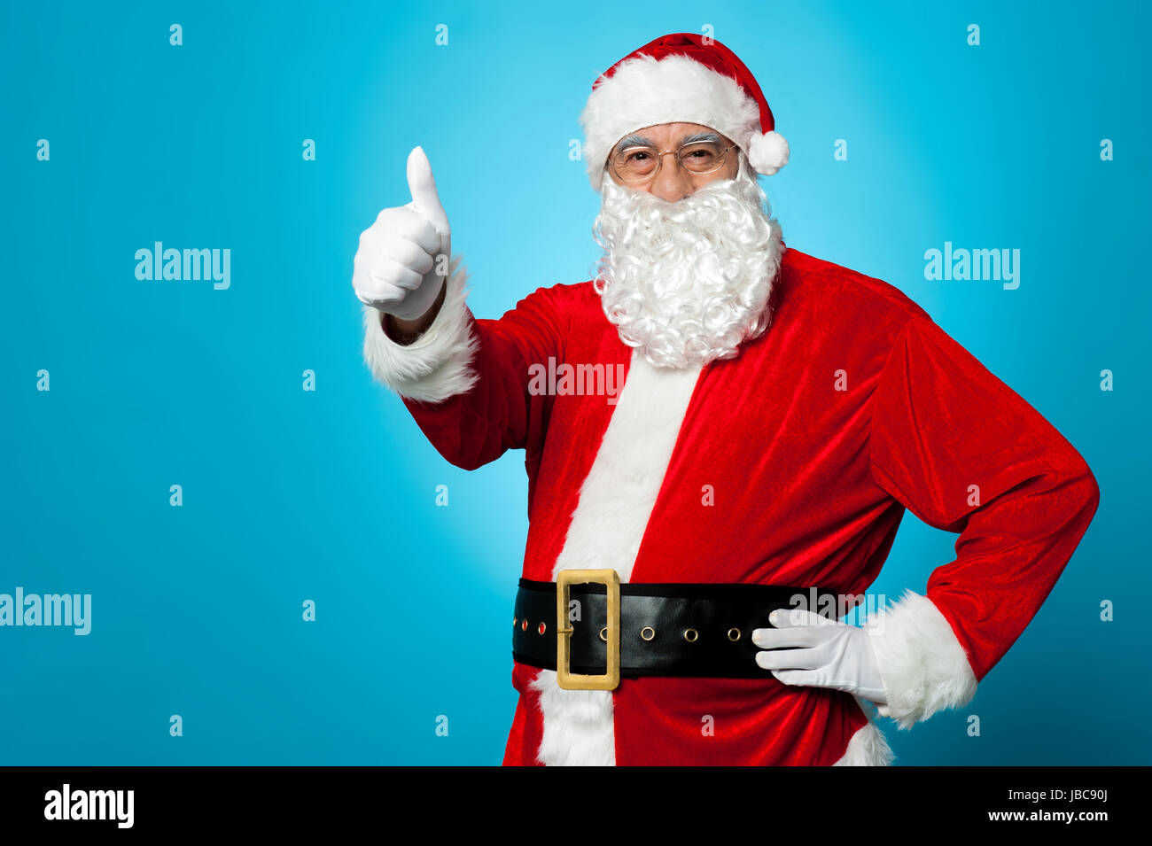 Father Santa gesturing thumbs up isolated against blue background Stock ...