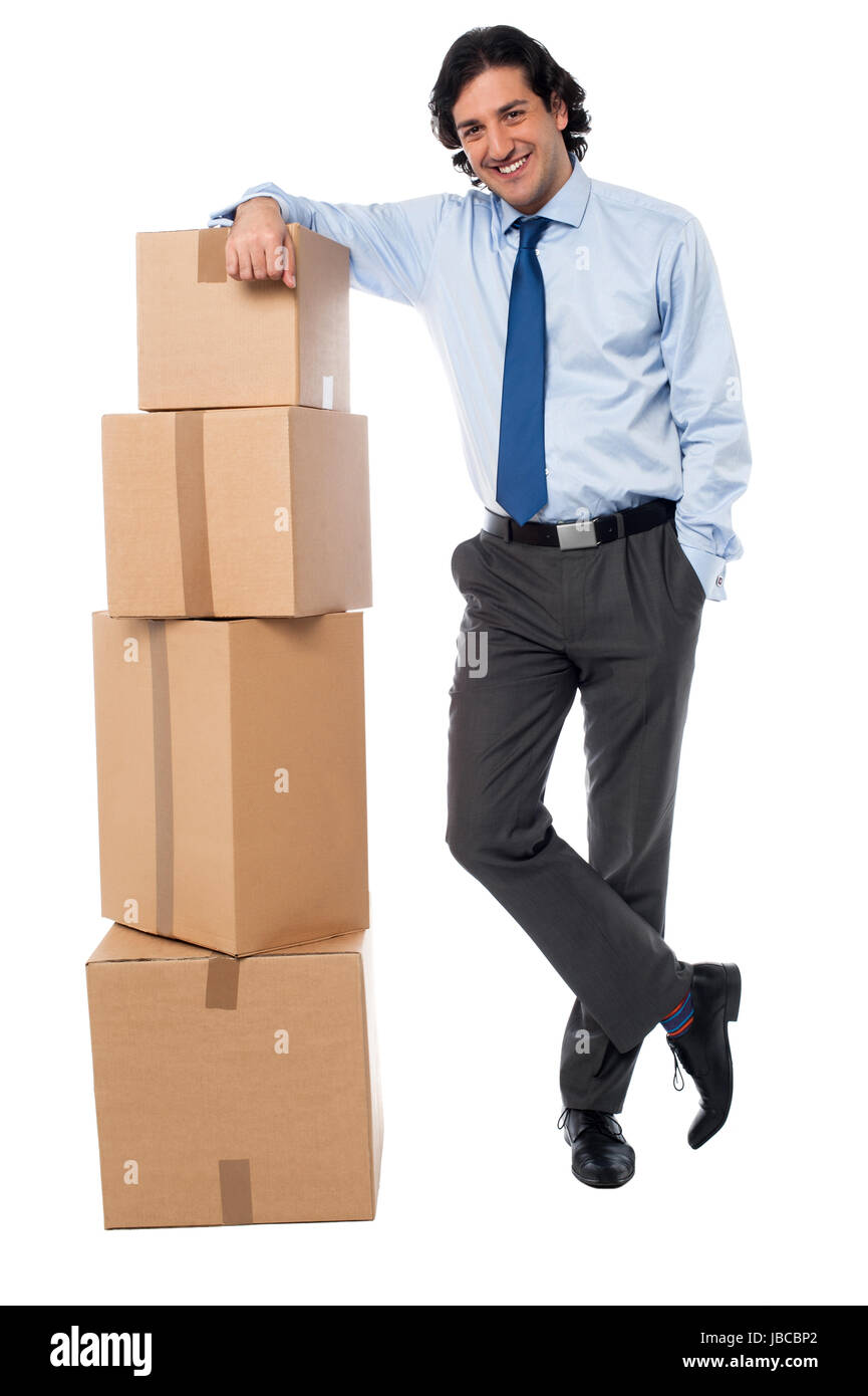 Corporate male standing beside stack of cardboard boxes Stock Photo - Alamy