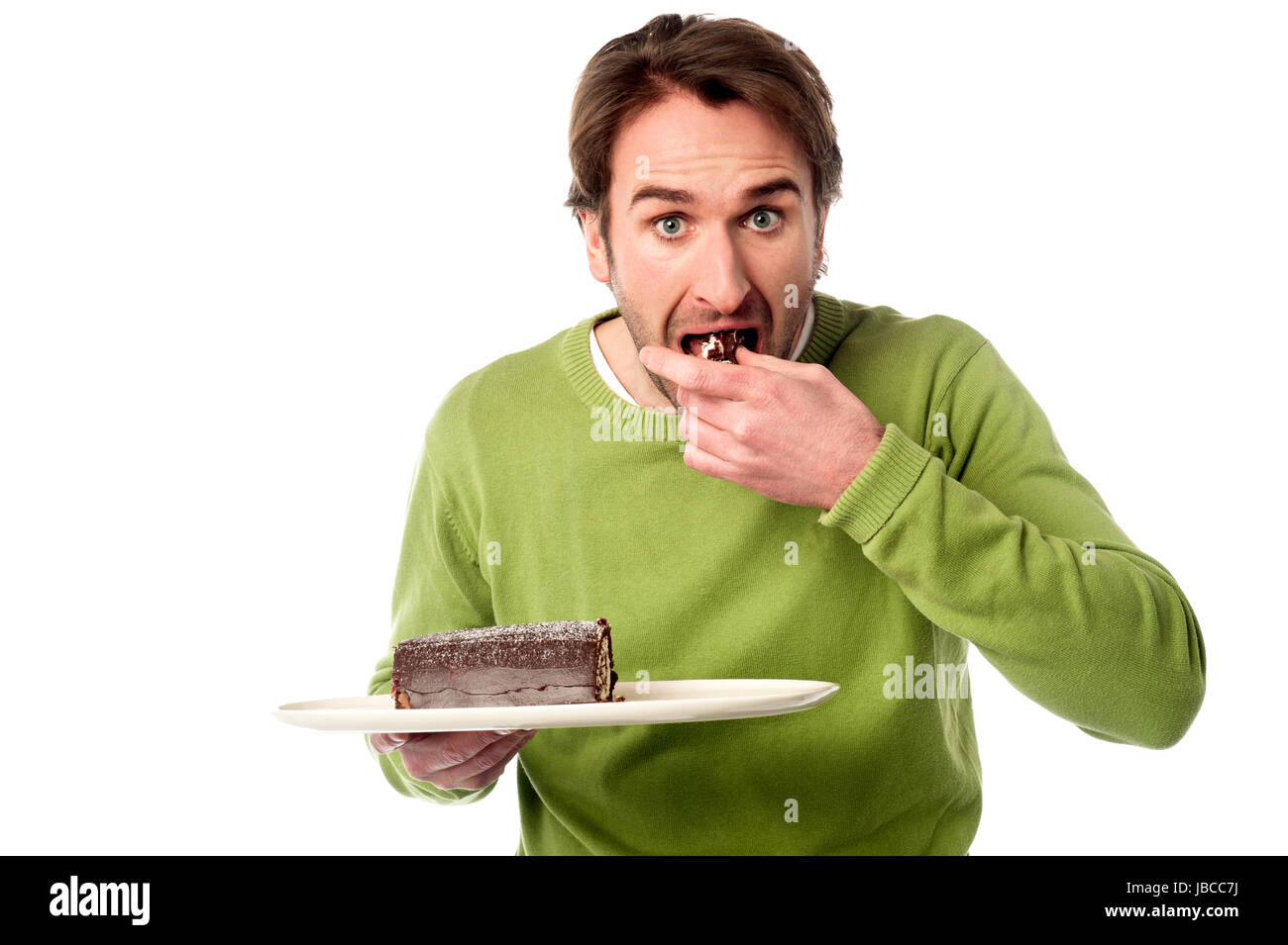 Young man eating chocolate cake in hurry Stock Photo - Alamy