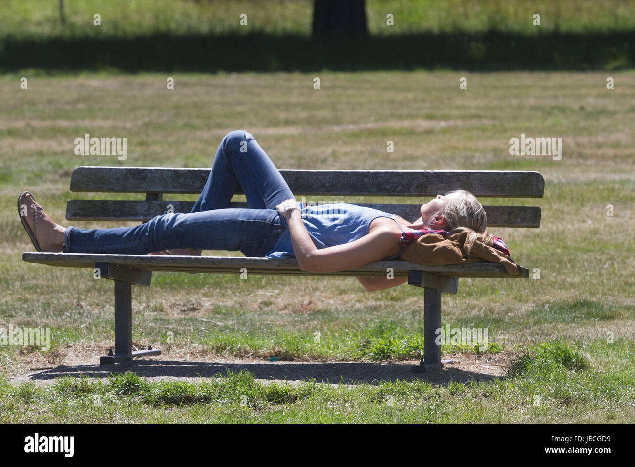 London UK. 10th June 2017. A woman relaxing and sunbathing on a bench ...