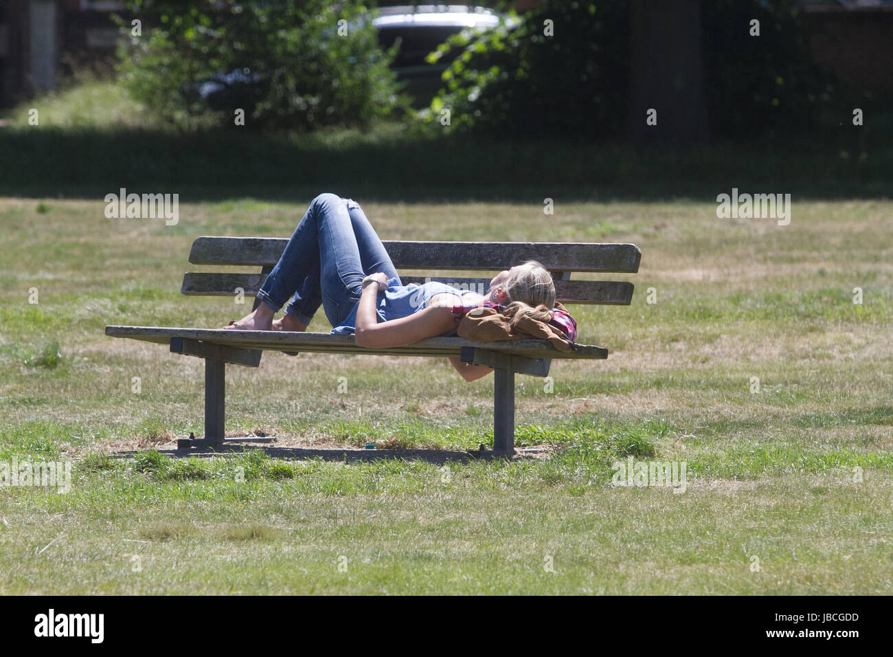 London UK. 10th June 2017. A woman relaxing and sunbathing on a bench ...