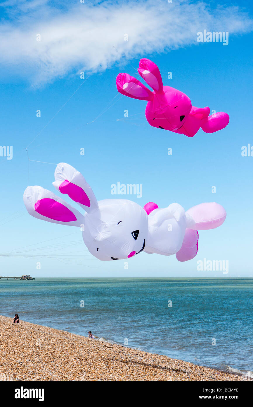 Two bunny shaped inflated kites, one white, other pink, flying against ...