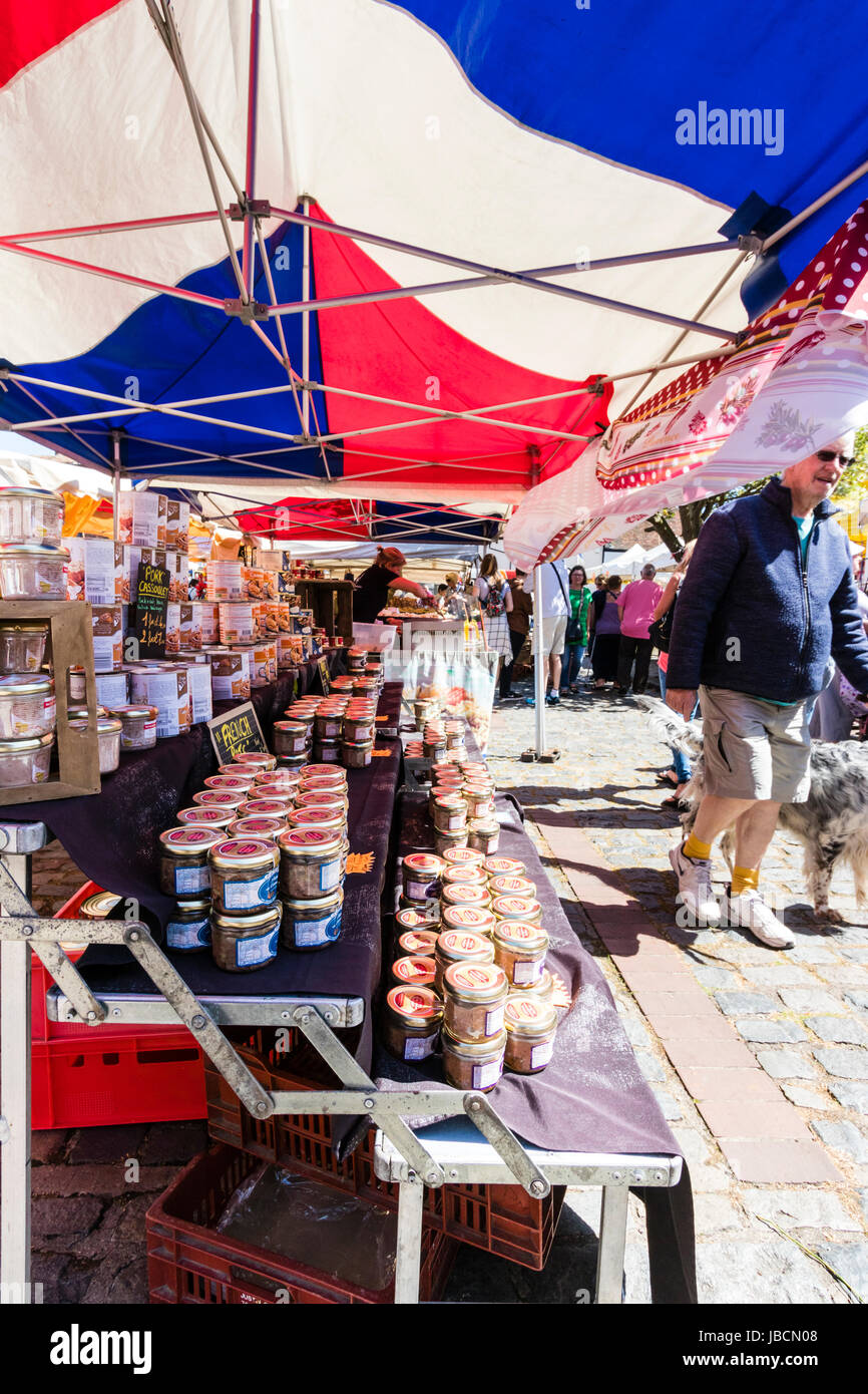 French market stall with customers looking at jars and tinned food ...