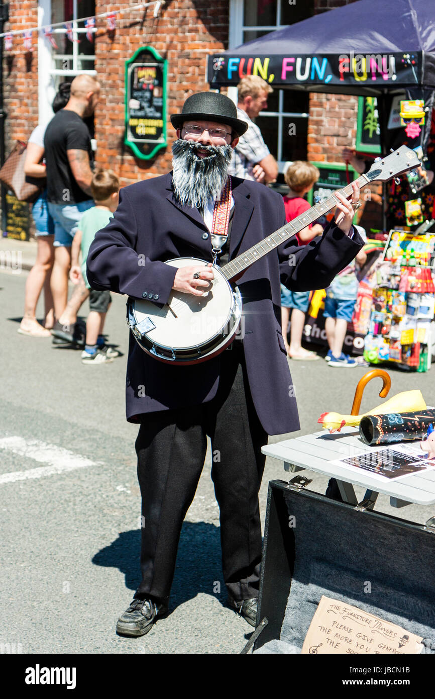 Street busker wearing black coat and bowler hat, playing banjo in the ...