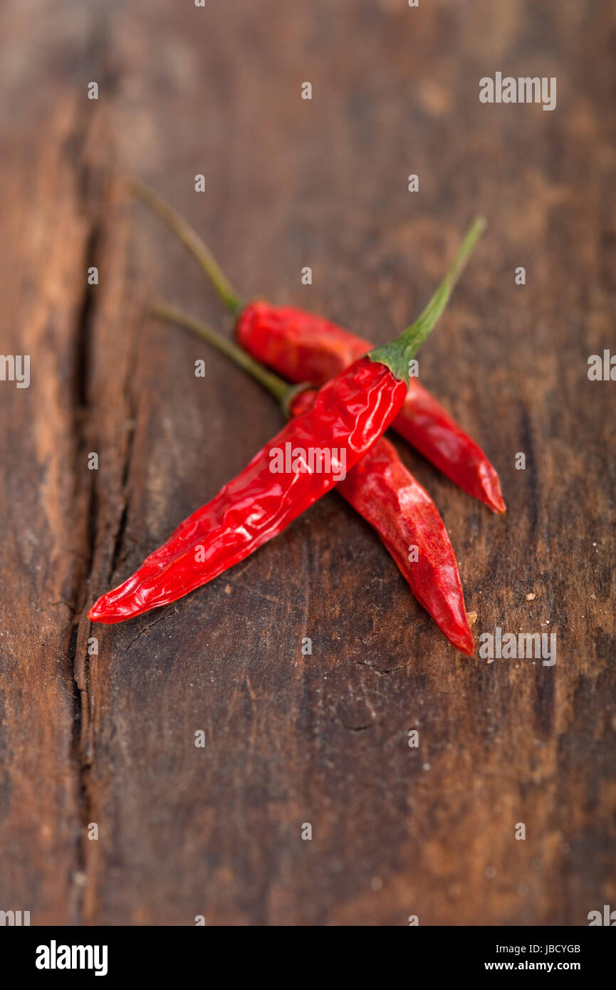dry red chili peppers over old wood table Stock Photo - Alamy