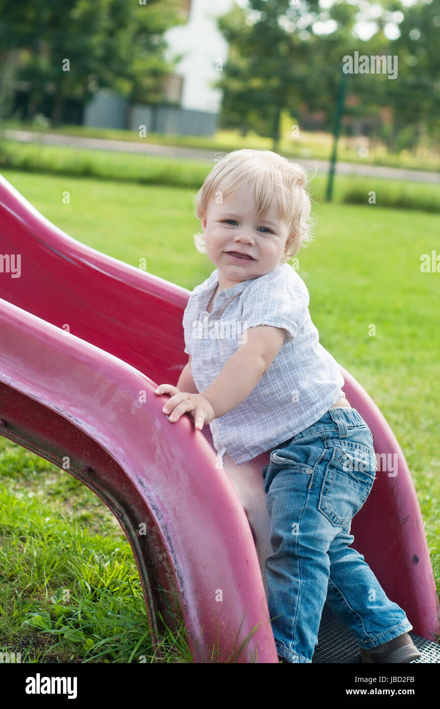 Smiling child playing on a baby slide outdoors Stock Photo - Alamy