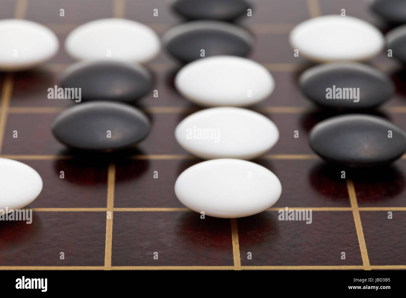 position of stones during go game playing on wooden goban close up ...