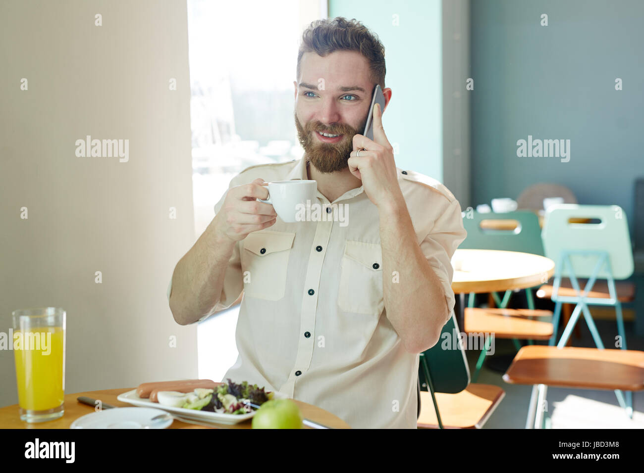Young agent having lunch in cafe and talking to client on cellphone ...