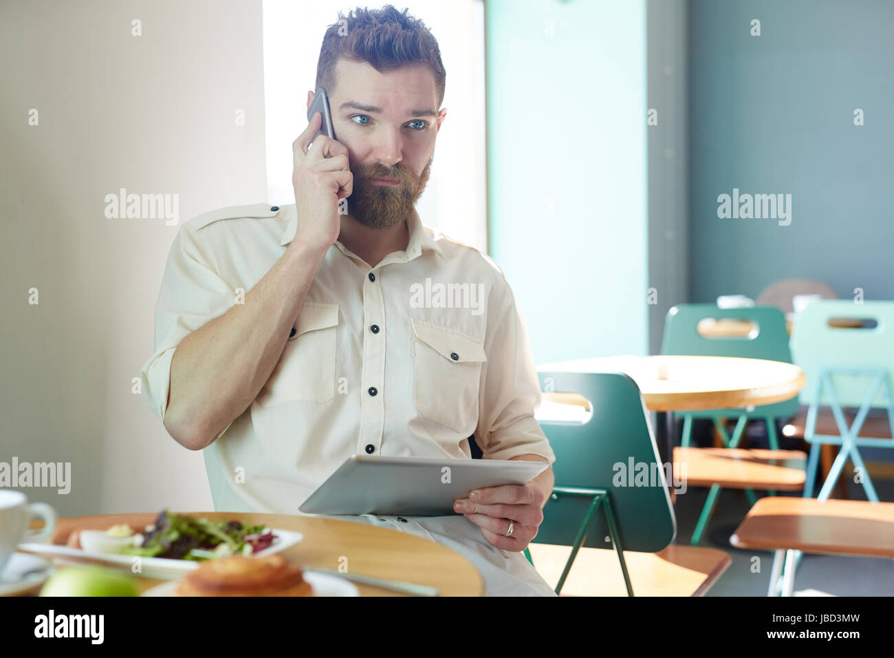 Busy agent phoning by table in cafeteria Stock Photo - Alamy