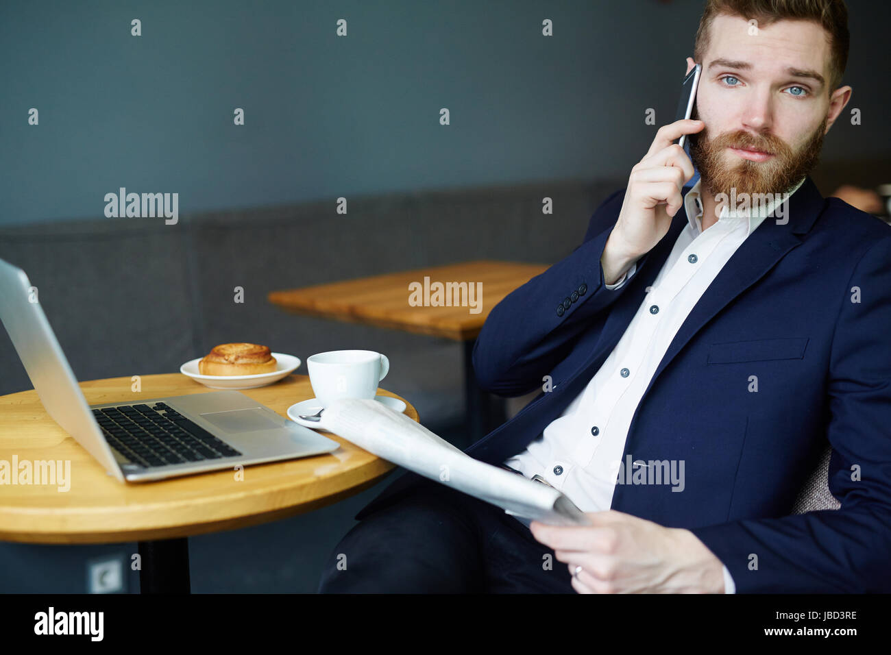 Confident ceo with newspaper calling in cafe Stock Photo - Alamy
