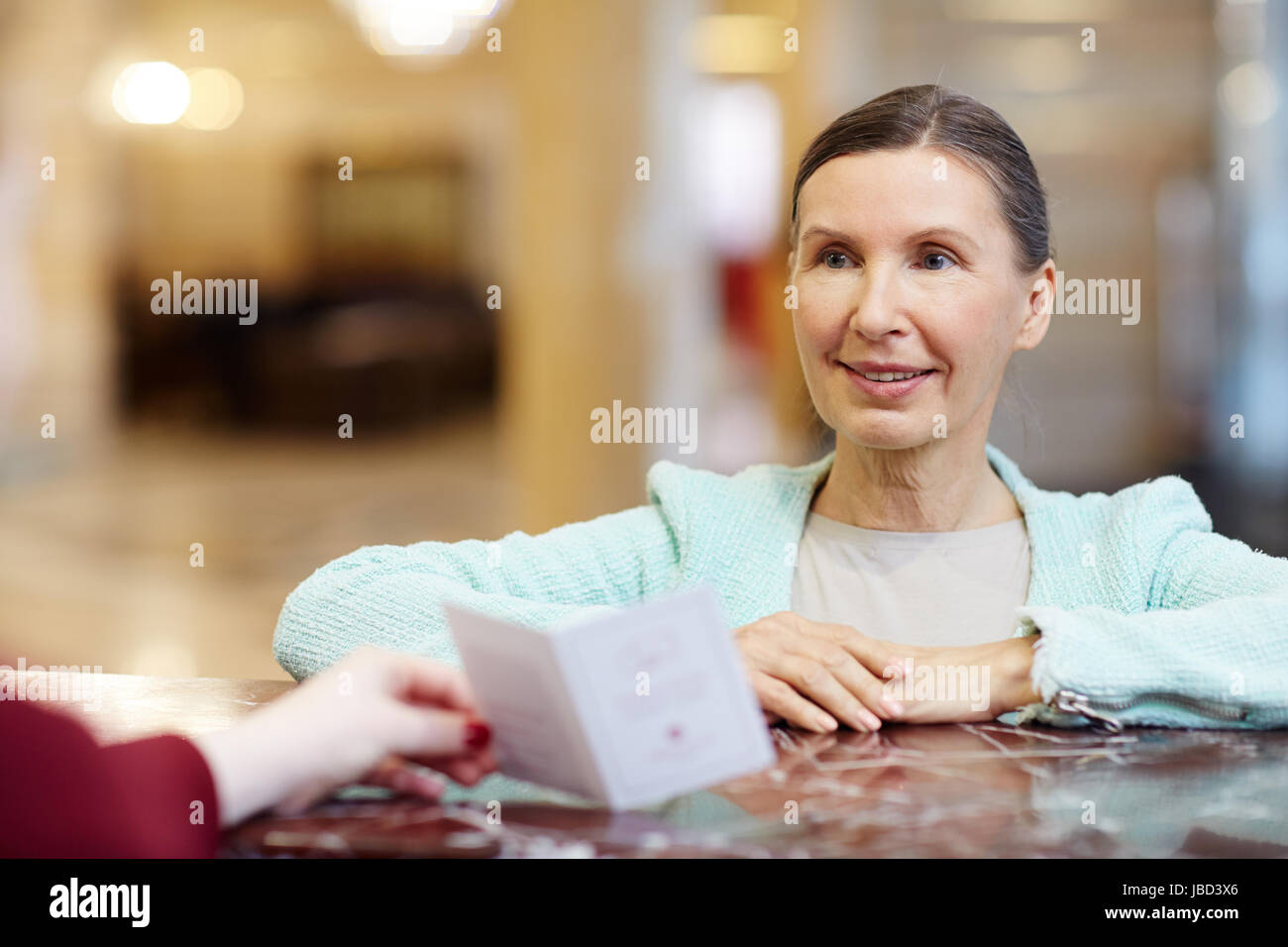 Aged tourist talking to receptionist in hotel lounge Stock Photo - Alamy