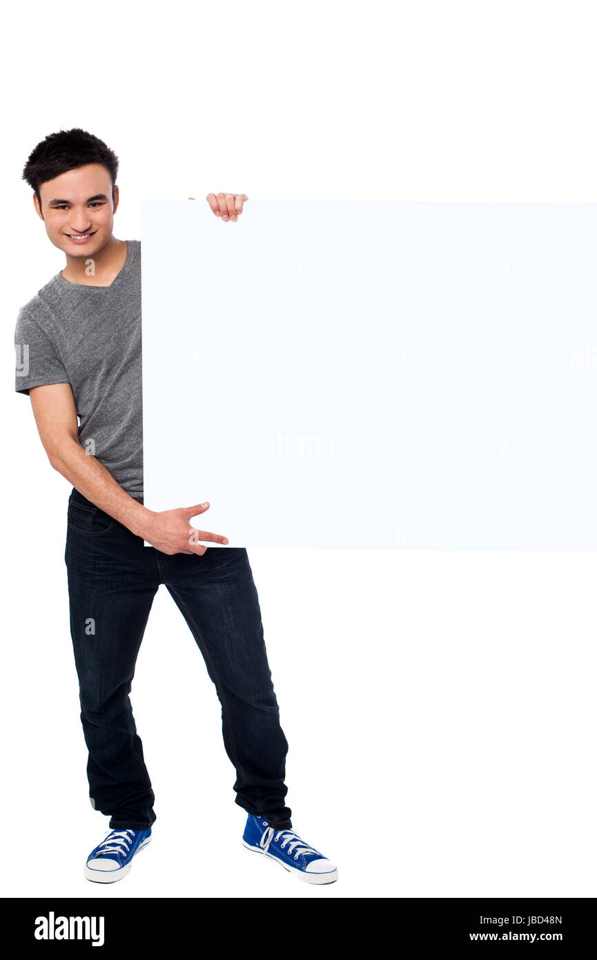 Smiling young guy holding blank white poster Stock Photo - Alamy