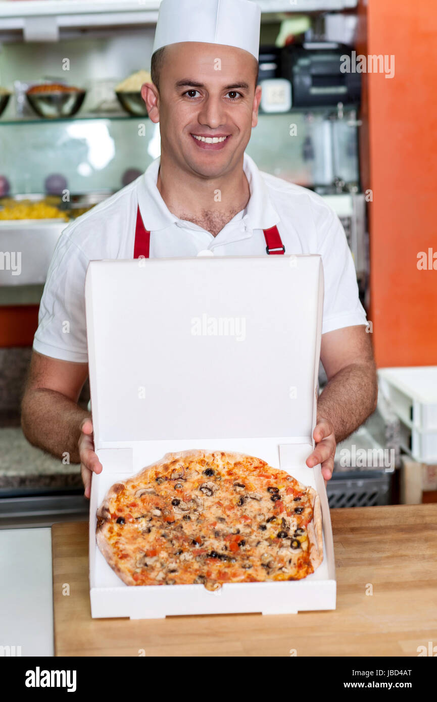 Young male chef presenting sample pizza Stock Photo - Alamy
