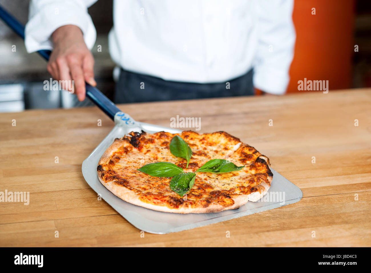 Chef placing freshly baked pizza on the table Stock Photo - Alamy