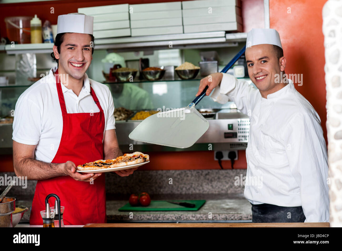 Chef handing over pizza to male assistant Stock Photo - Alamy