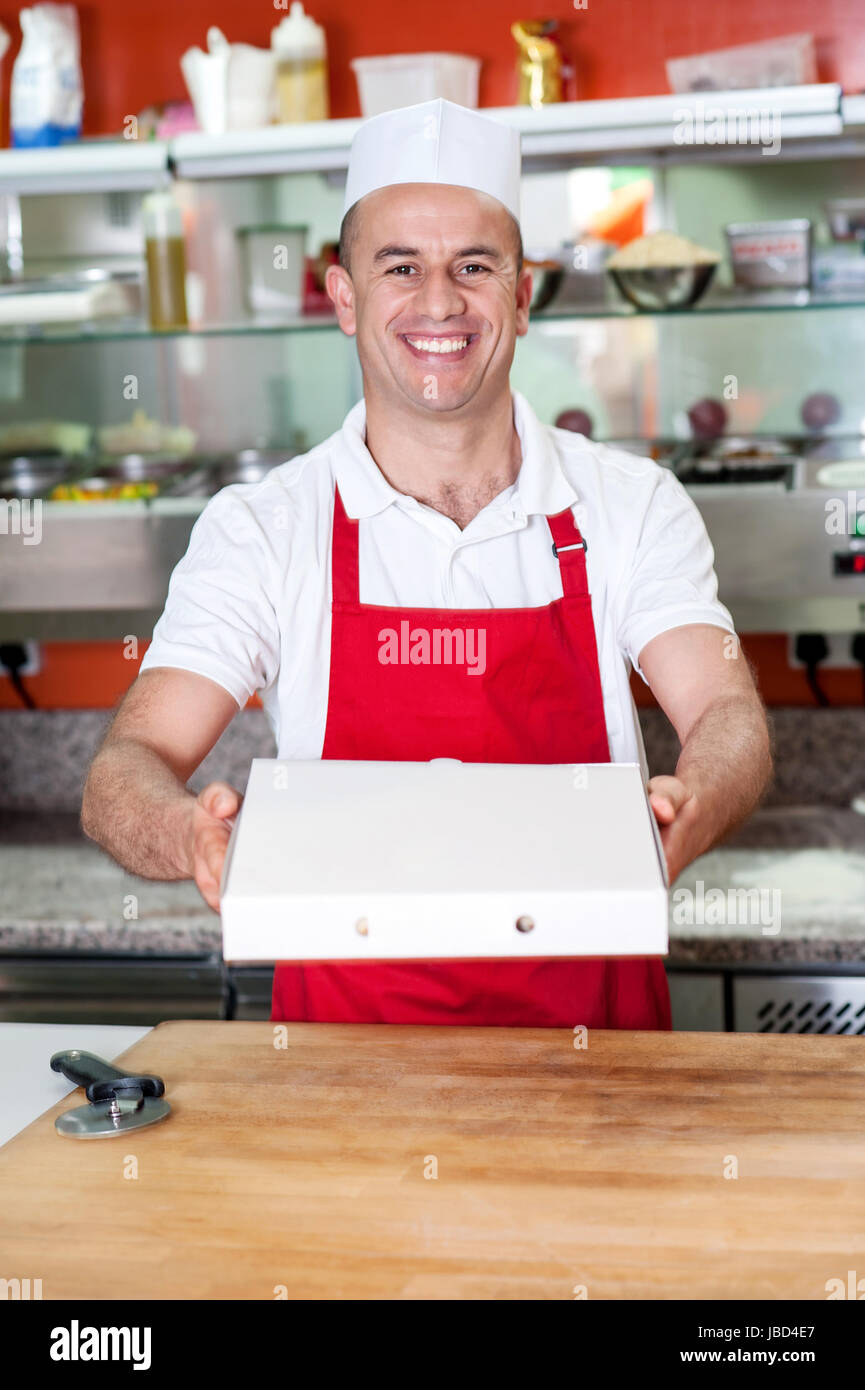 Young male chef handing over pizza Stock Photo - Alamy