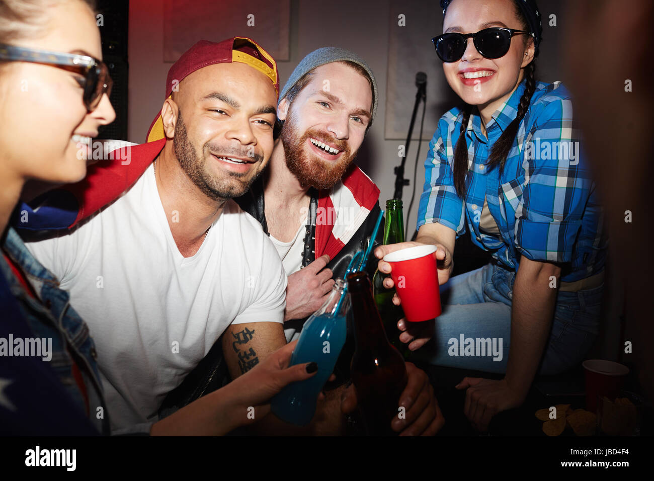 Group of smiling young party people, men and woman, drinking beer and ...