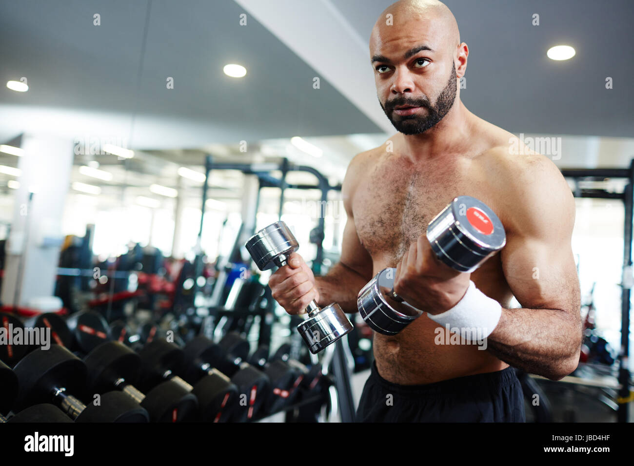 Portrait of strong muscular man pumping muscles working out with ...