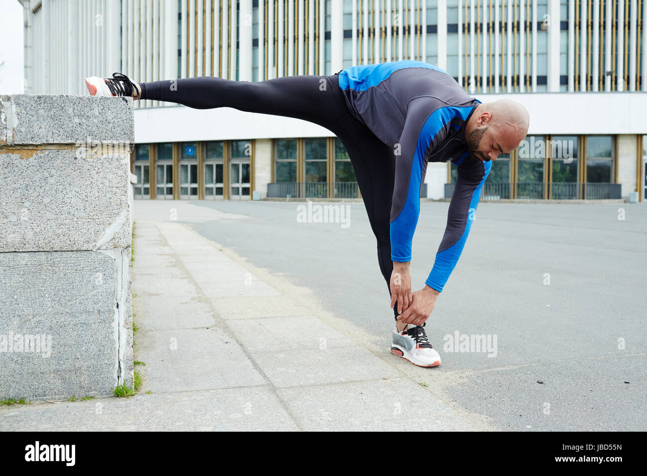 Sporty guy in activewear bending while making stretch exercise Stock ...