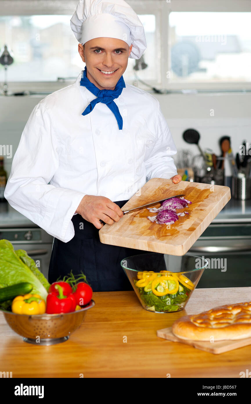 Chef pushing chopped vegetables into a glass bowl Stock Photo - Alamy